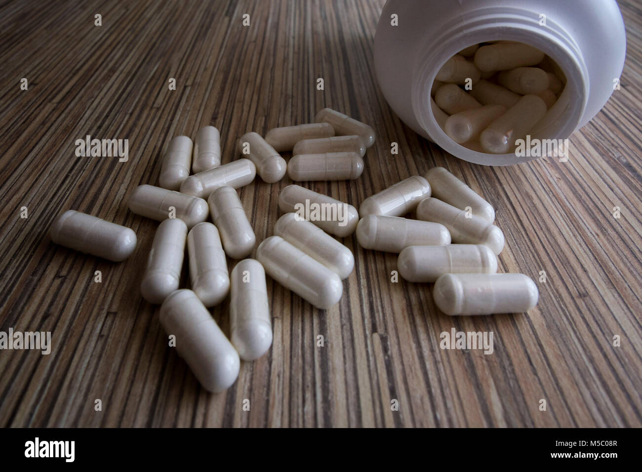 Pile of scattered capsules on a wooden background. white capsule ...