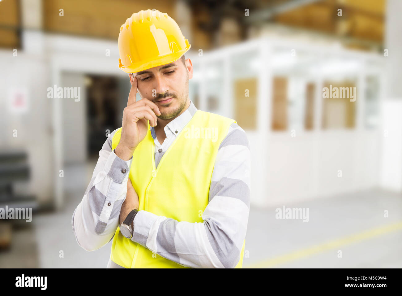 Thoughtful engineer thinking about factory problems and solutions ...