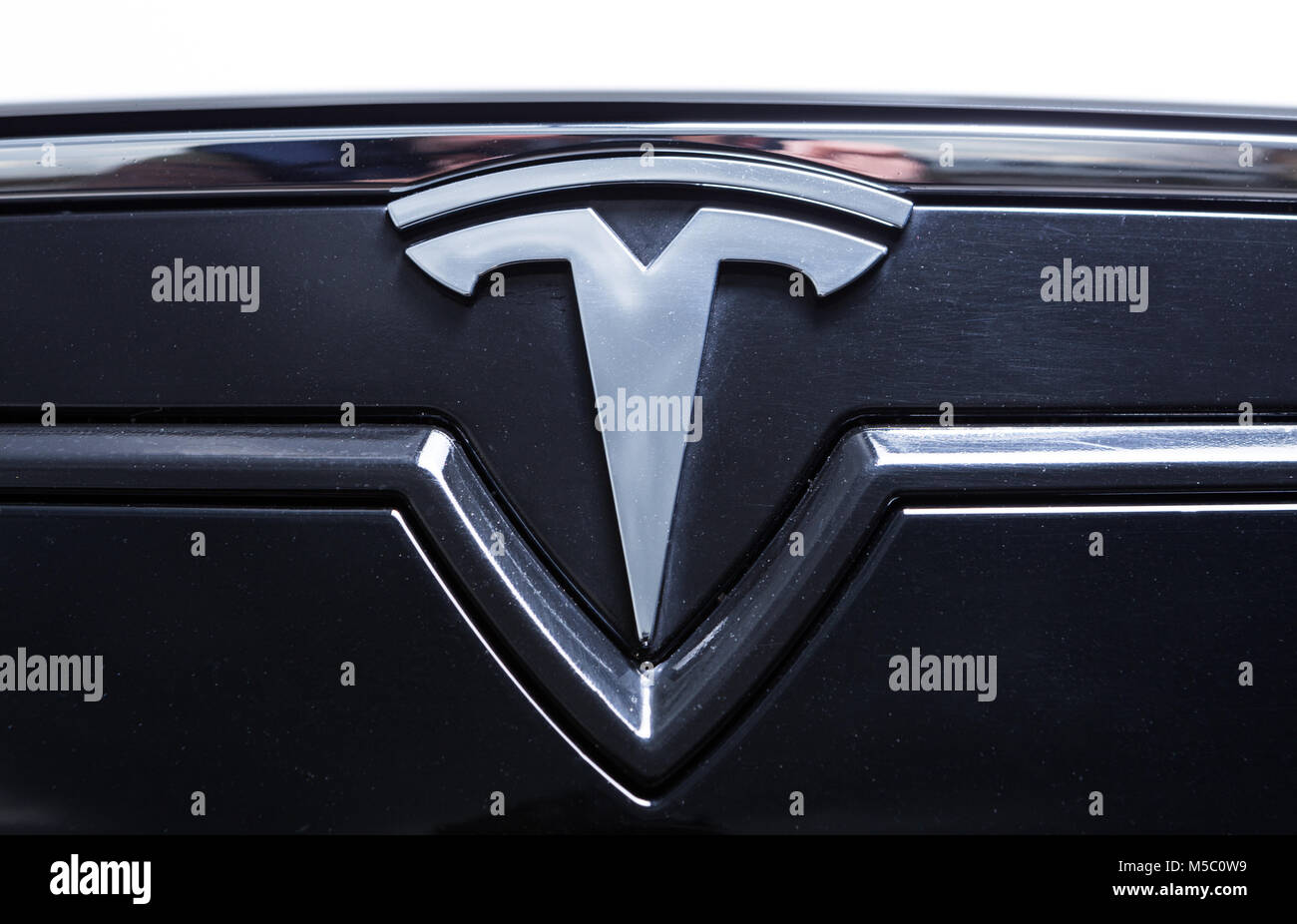Close-up of original metalic electric Tesla car logo on front side ...