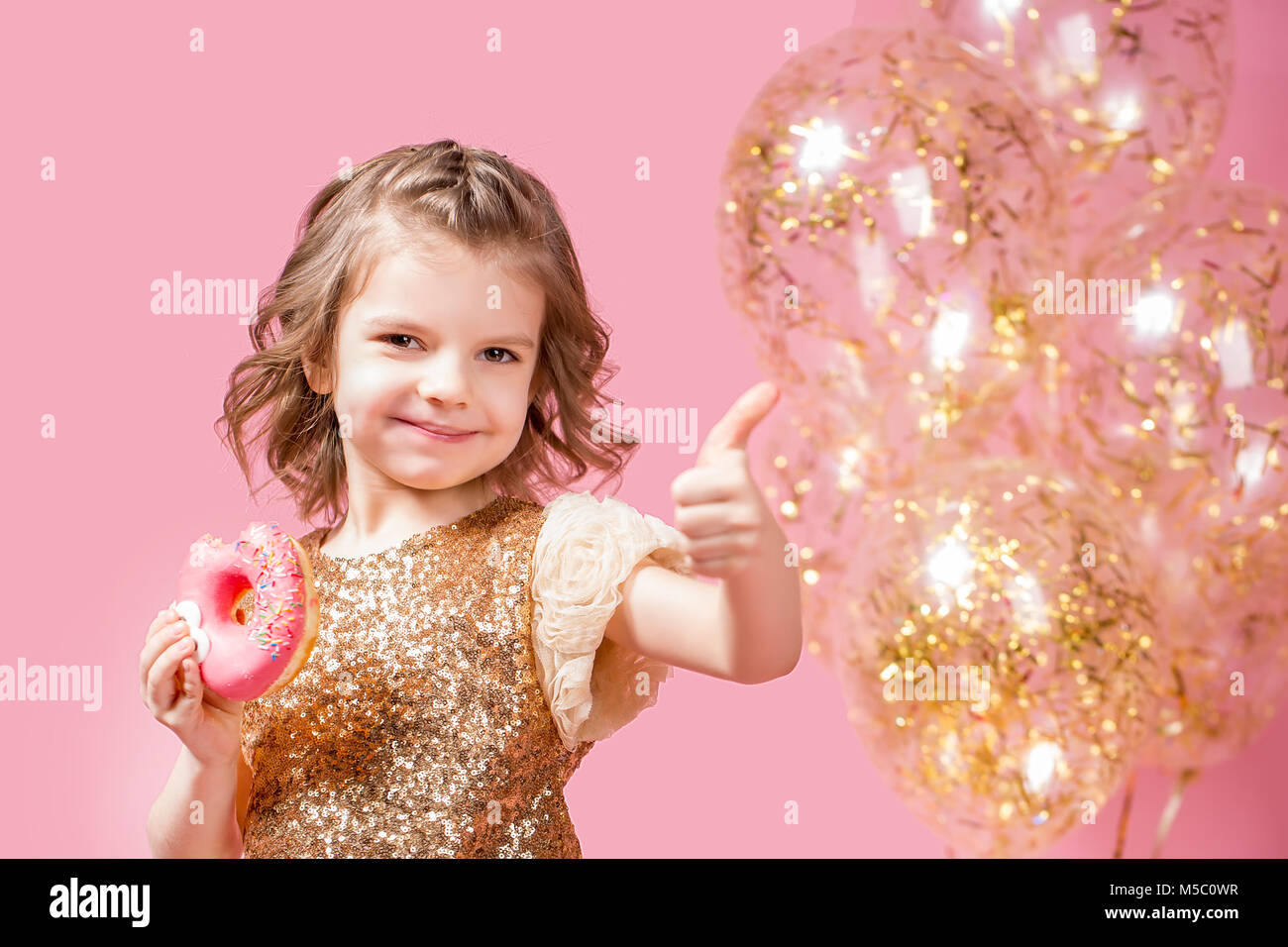 Girl holding donut and gesturing thumb up Stock Photo - Alamy