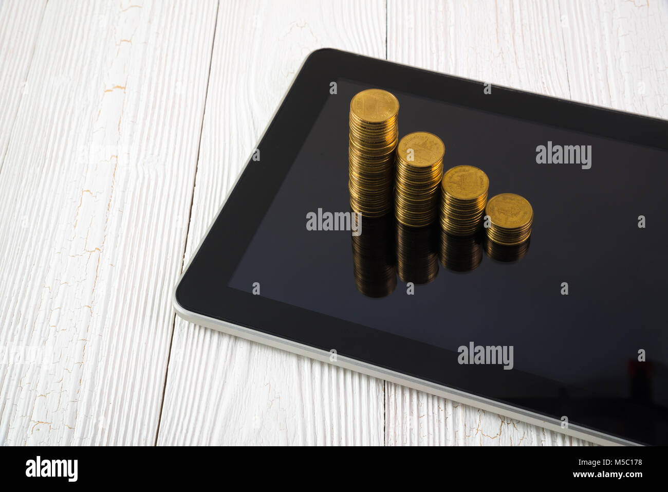 Step of coin stack on tablet computer screen on white working table ...