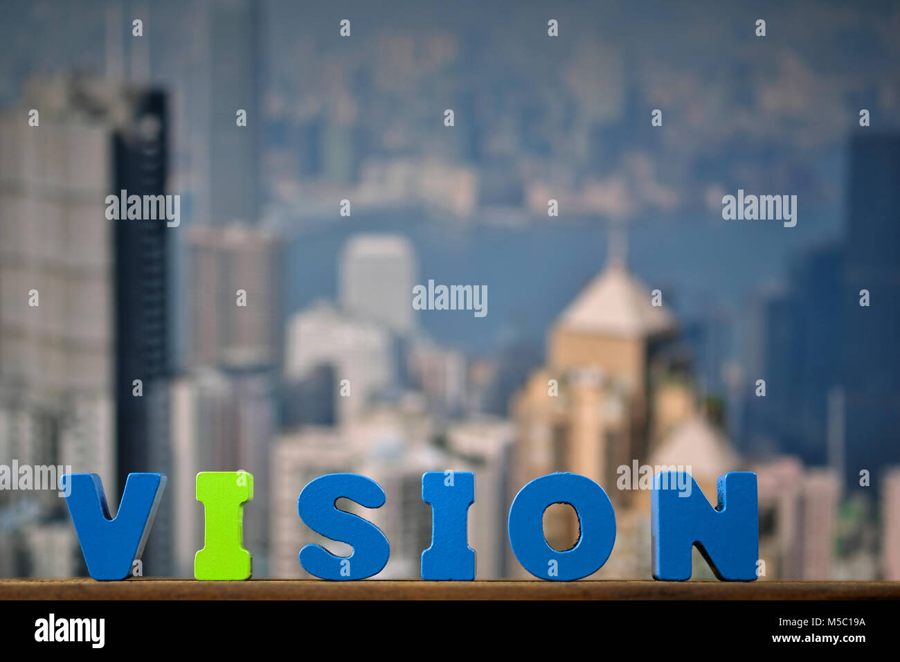 VISION text on top wooden working table with city and office building ...