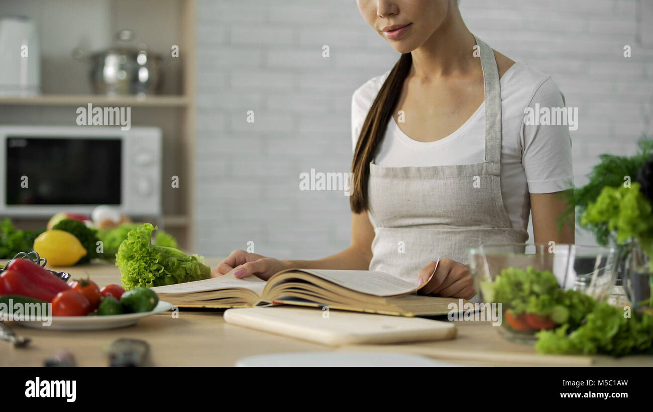 Asian woman reading cooking book and choosing dinner recipe, healthy ...