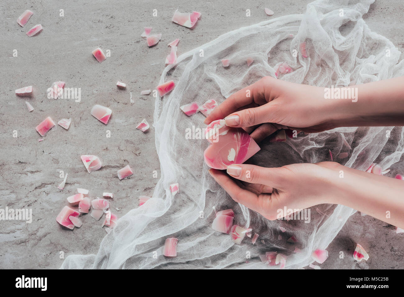 cropped view of hands with pink heart shaped soap on white gauze on ...