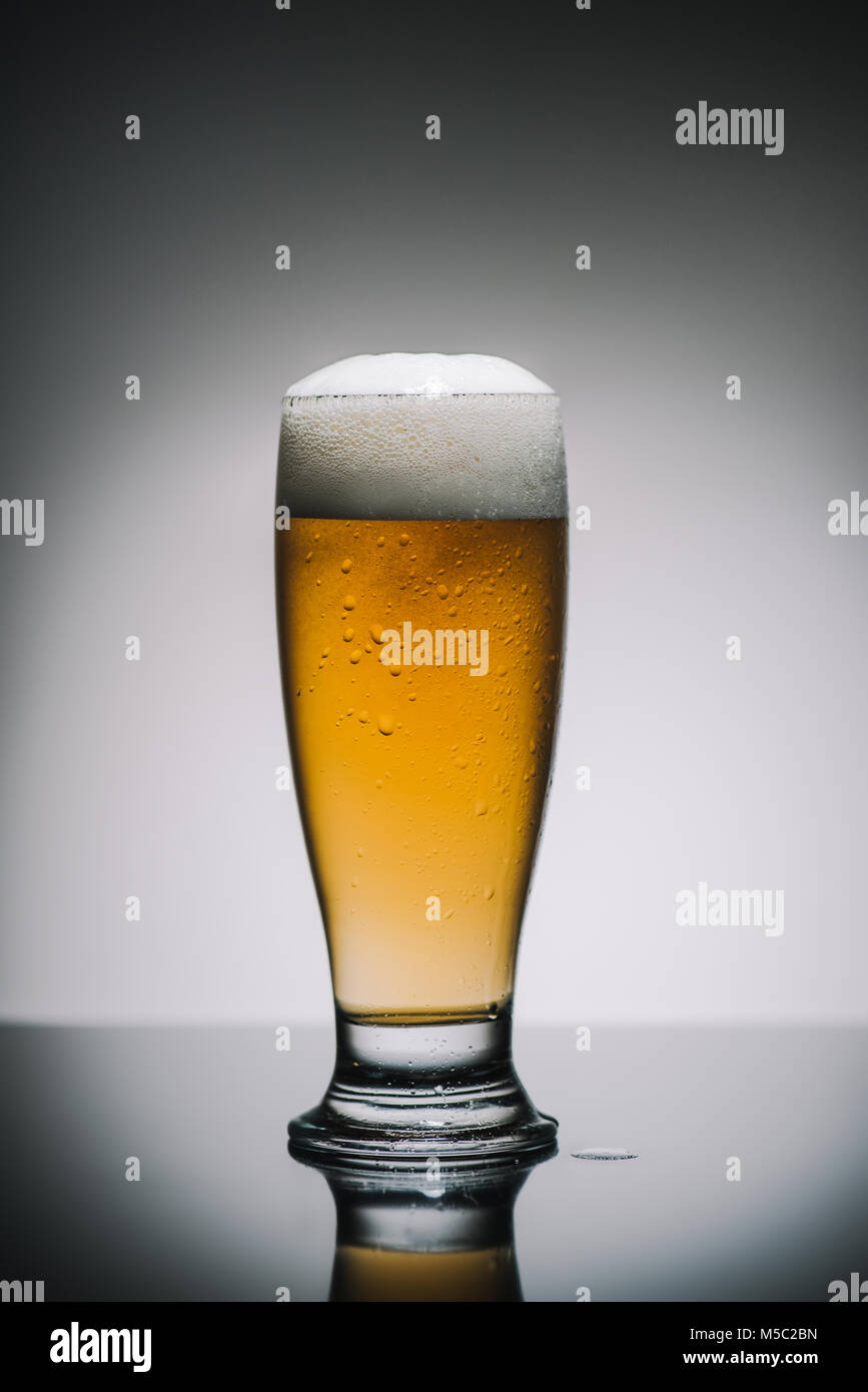 full glass of beer with foam on table Stock Photo - Alamy