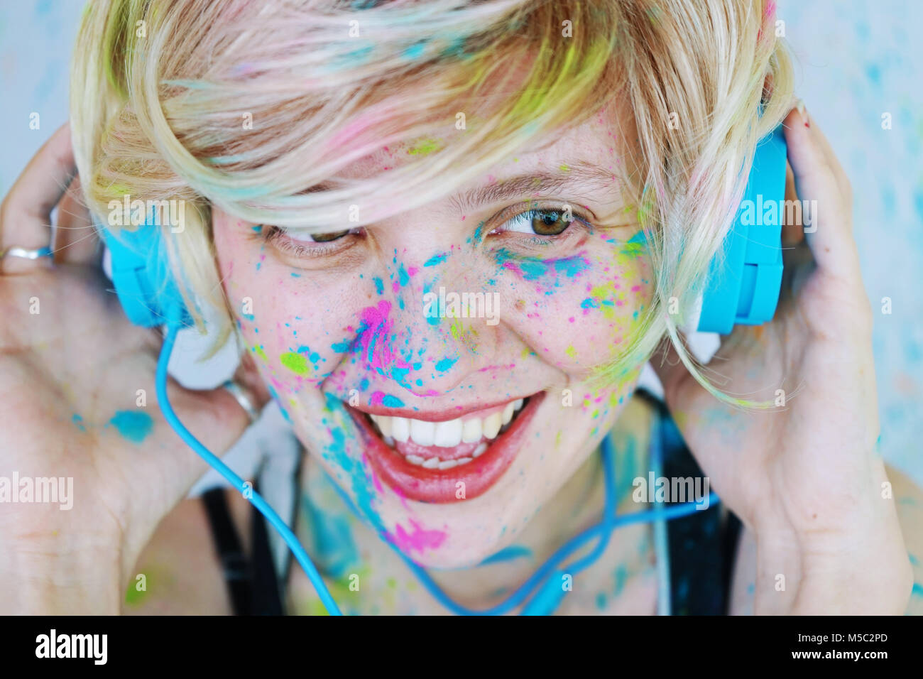 Young woman with paint in her face is listening to music Stock Photo ...