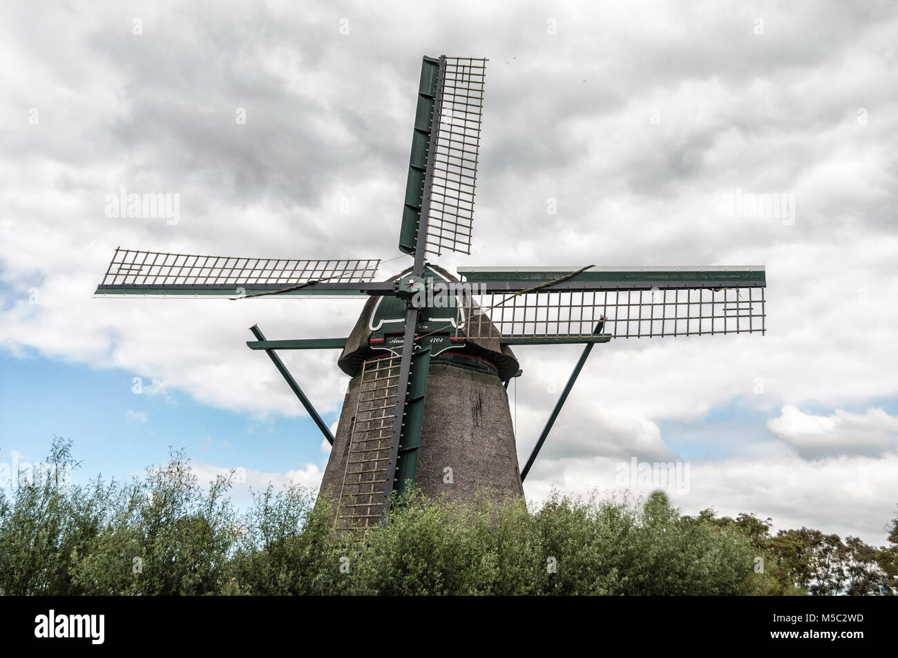 Dutch windmill surrounded by green trees with a blue sky cloudy ...
