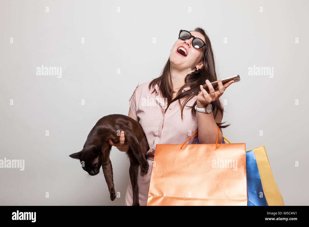 Powerful laughing woman screams holding cat and bags Stock Photo - Alamy