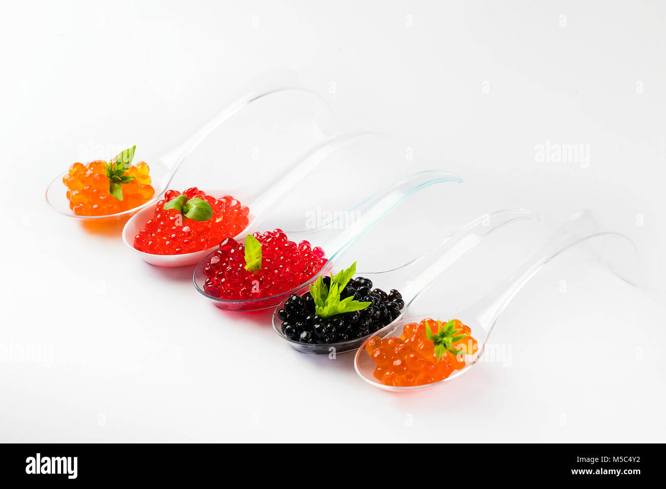 Plastic spoons with fish caviar on a white background Stock Photo - Alamy
