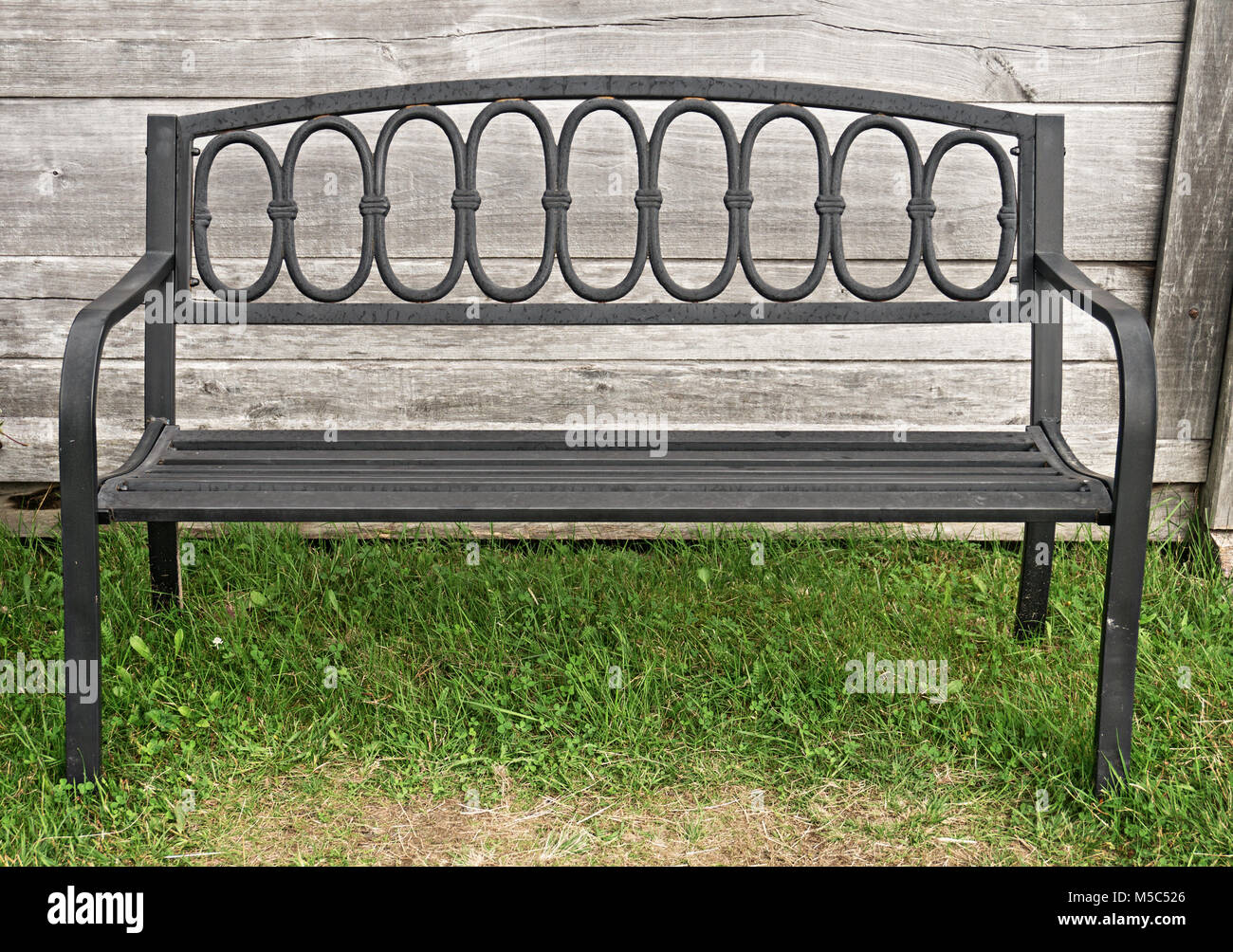 Old metal forged bench near the wooden wall Stock Photo - Alamy