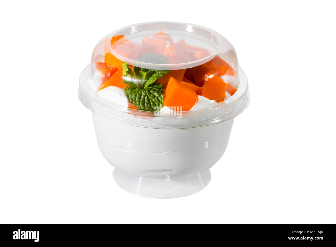 Creamy cream dessert in a plastic cup decorated with berries on a white ...