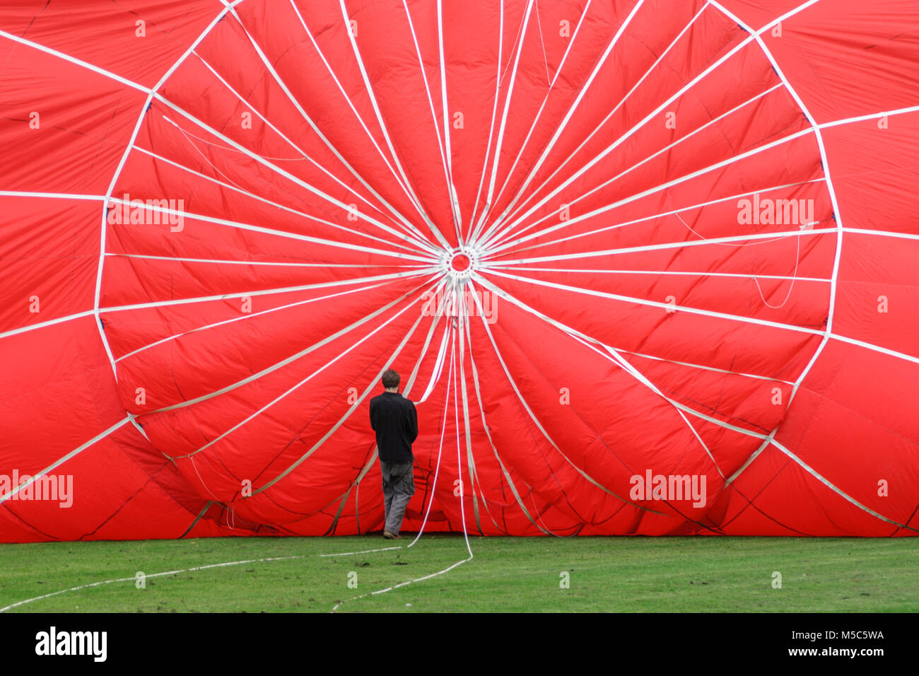 A young man holds on to the rigging of a hot air balloon while it is ...