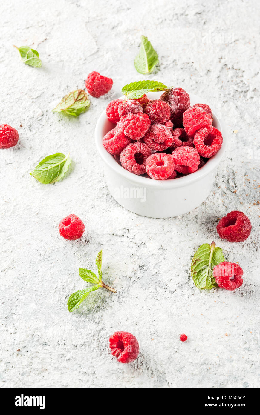 Fresh raspberries with mint in small bowl, on grey stone background ...
