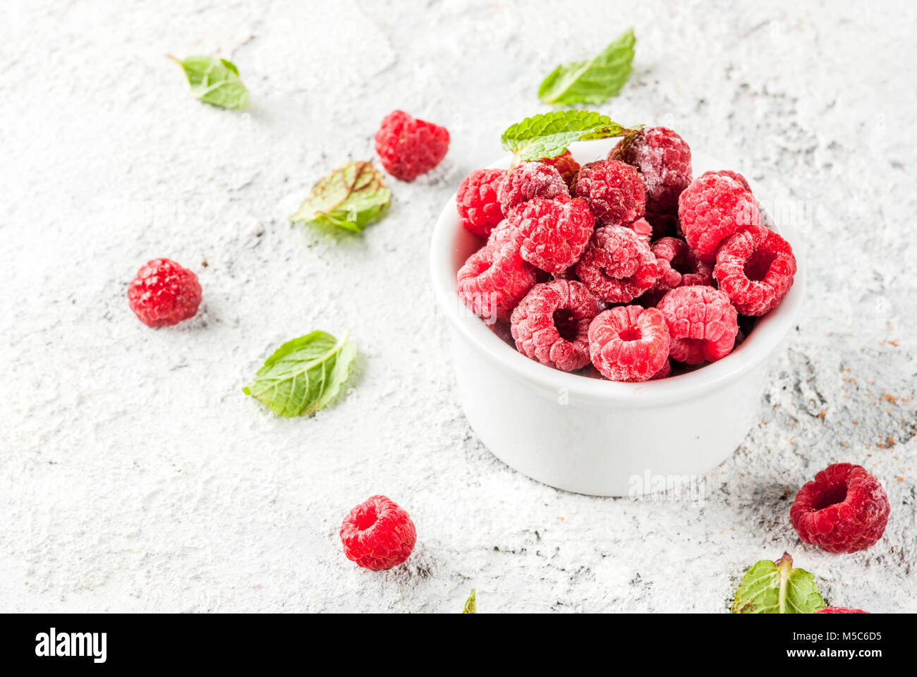 Fresh raspberries with mint in small bowl, on grey stone background ...