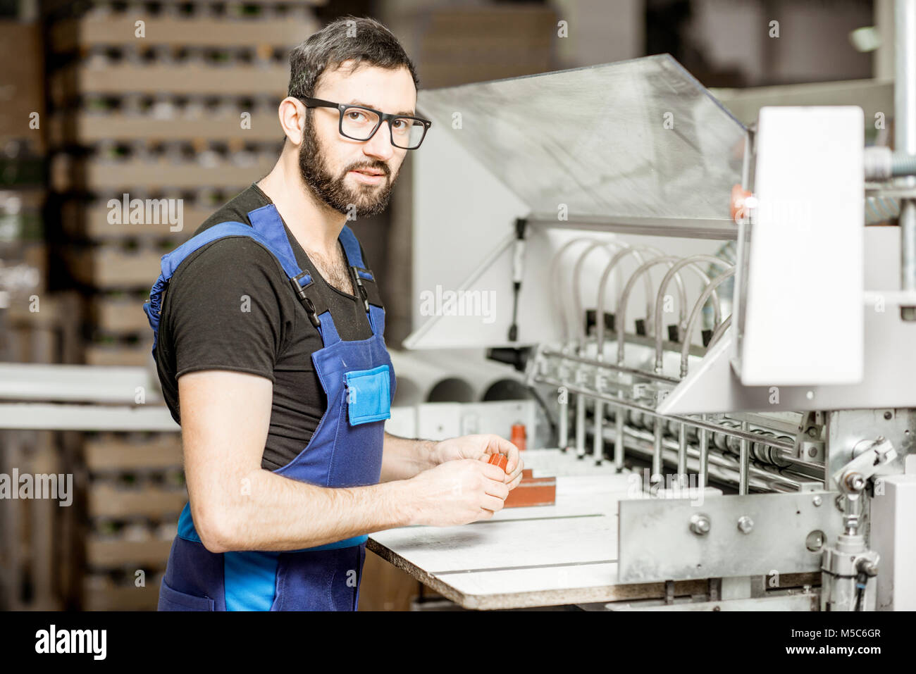 Man working with paper pipe machine Stock Photo - Alamy