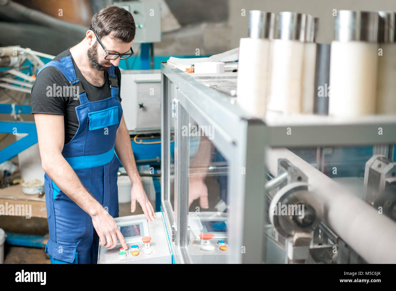 Man operating machine which makes paper tubes Stock Photo - Alamy