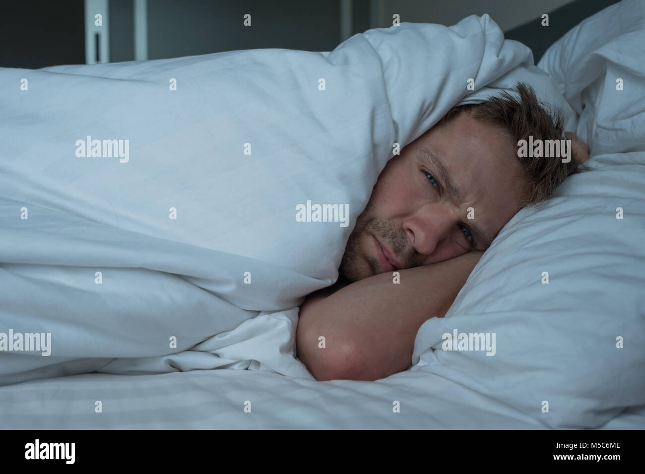 Depressed man lying in his bed and feeling bad Stock Photo - Alamy