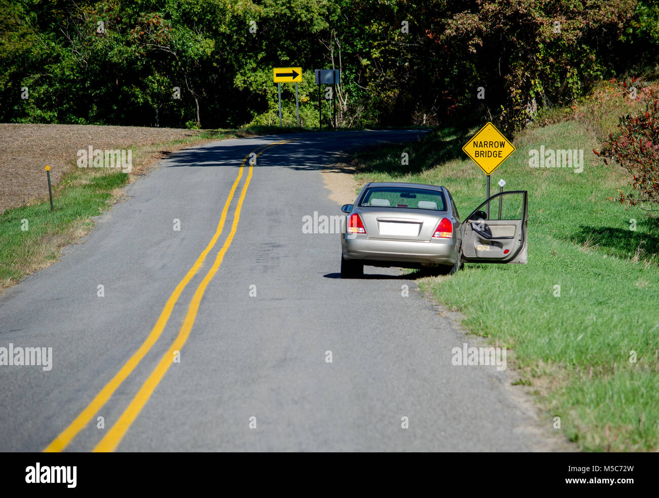 An abandoned car is parked on a remote country road with an open car ...