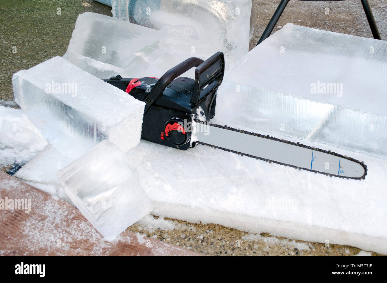 a small chain saw sits among blocks of ice at a ice sculpture ...