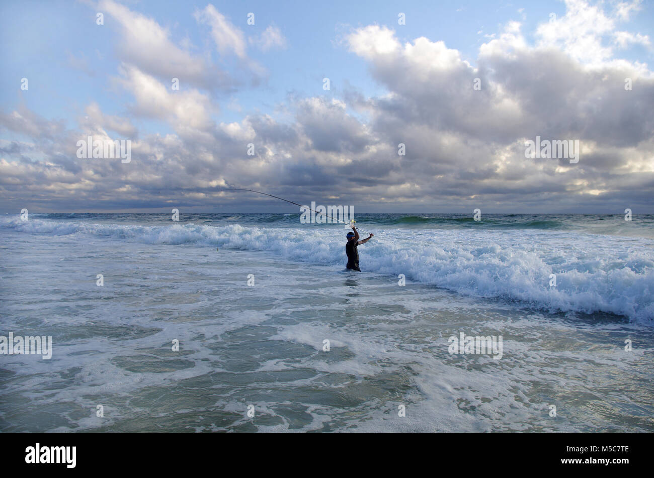 Surf fisherman into the waves. Fishing scene. surf casting Stock Photo ...