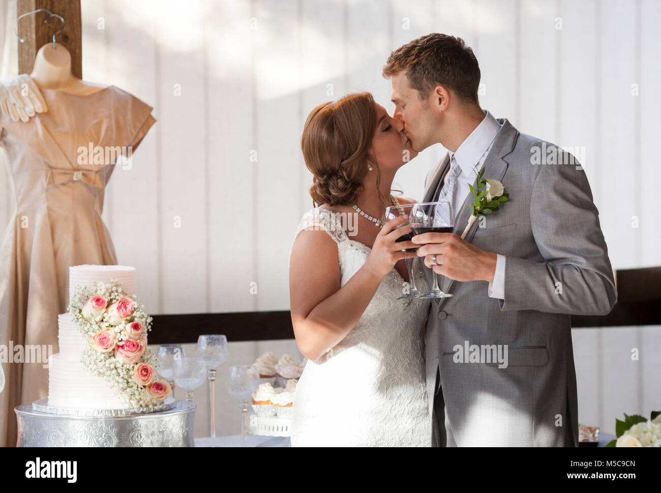Bride and groom at cake cutting during reception doing wine toast with ...