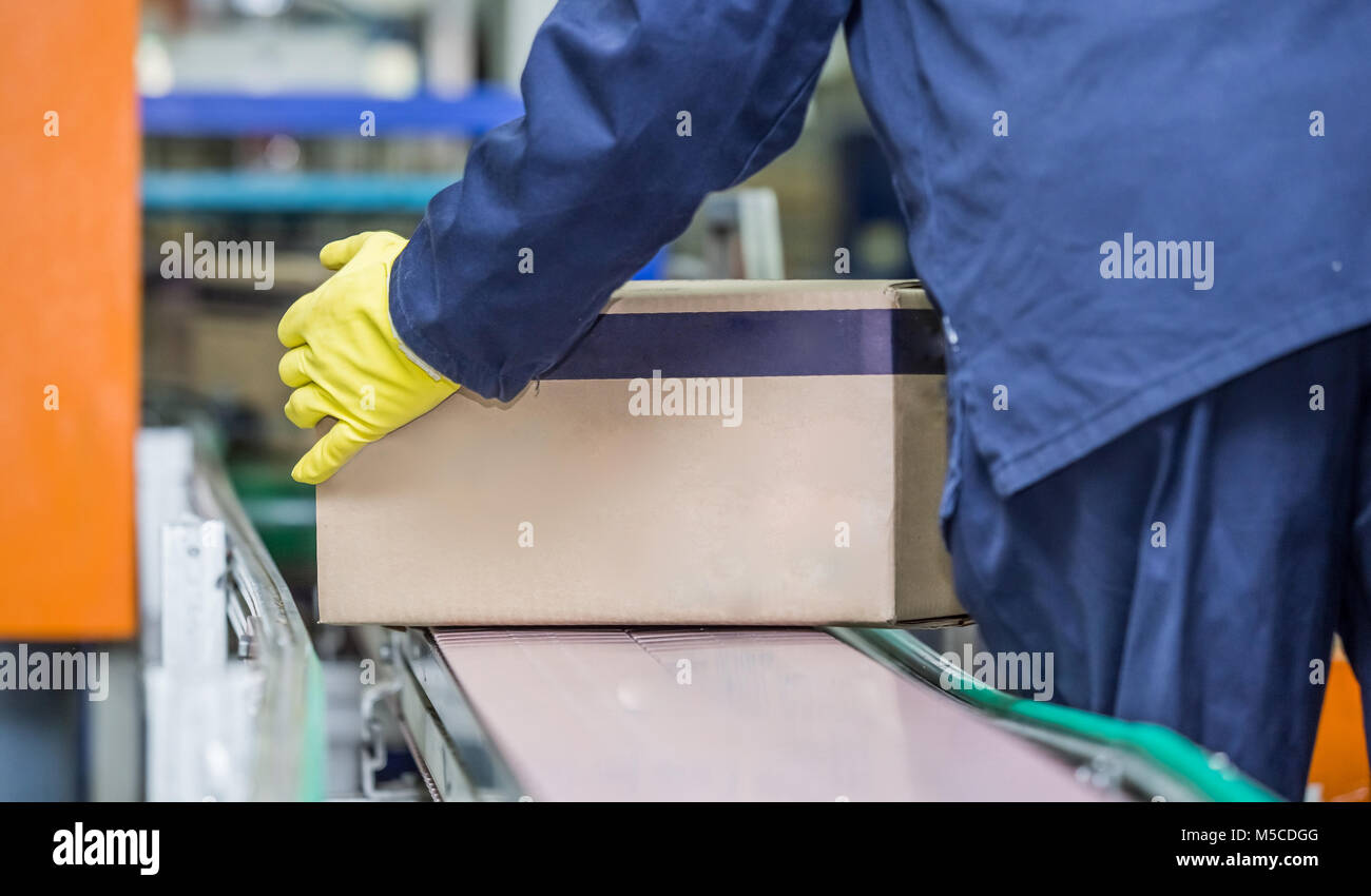 Worker lifting box off production line. Packaging plant with a box ...