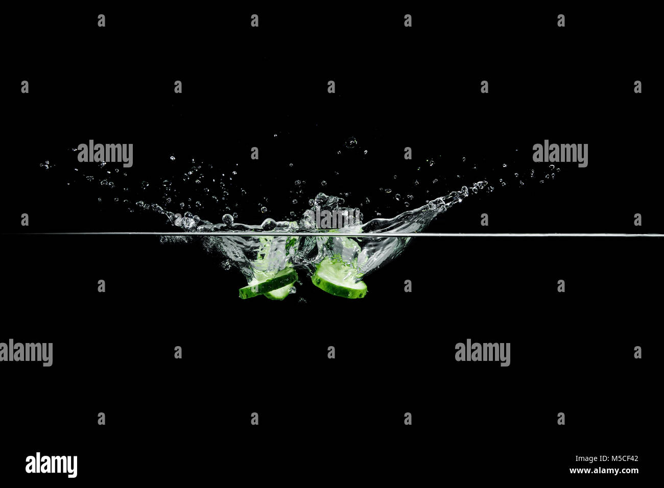 green cucumber slices in water with splash on black background Stock Photo - Alamy