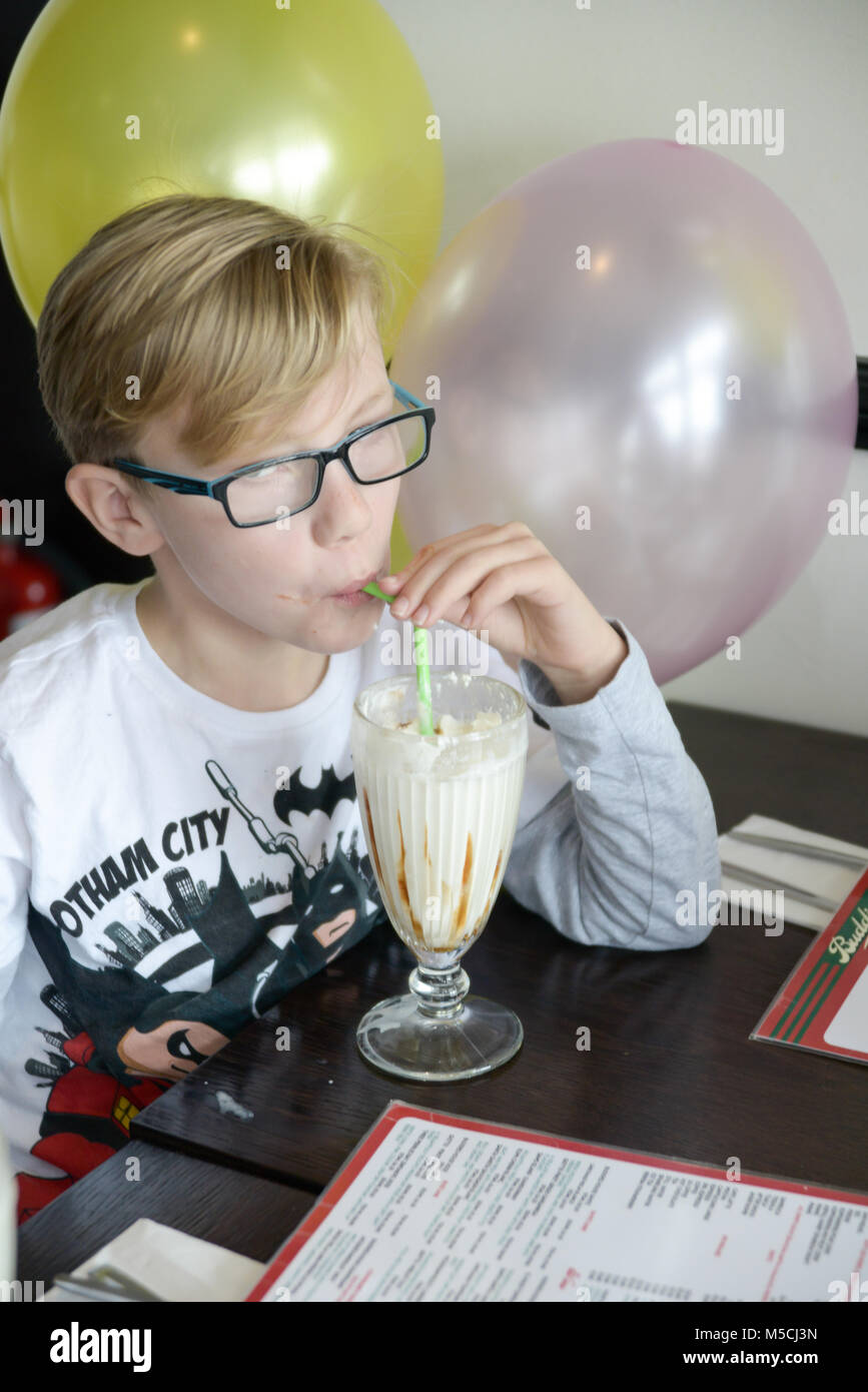 A child drinks a milkshake whilst sitting at a party table Stock Photo ...