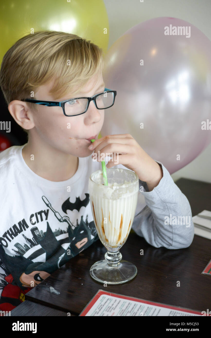 A child drinks a milkshake whilst sitting at a party table Stock Photo ...