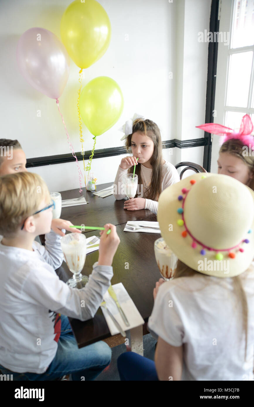 Five young children are sitting at a party table eating fried food and ...