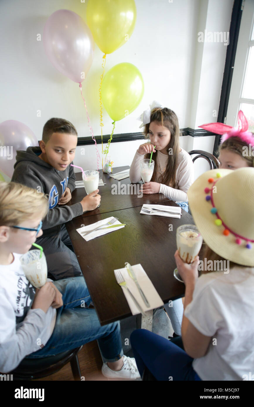 Five young children are sitting at a party table eating fried food and ...