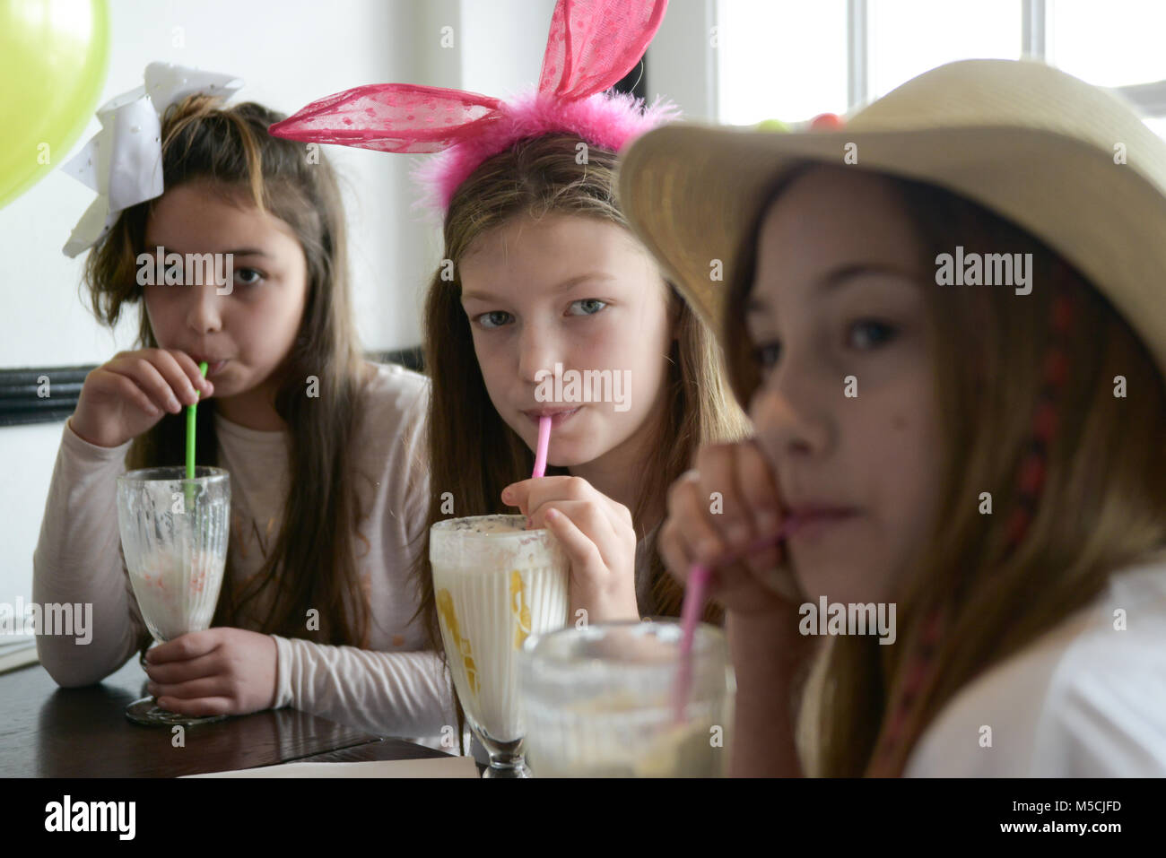 Three young children are sitting at a party table eating fried food and ...