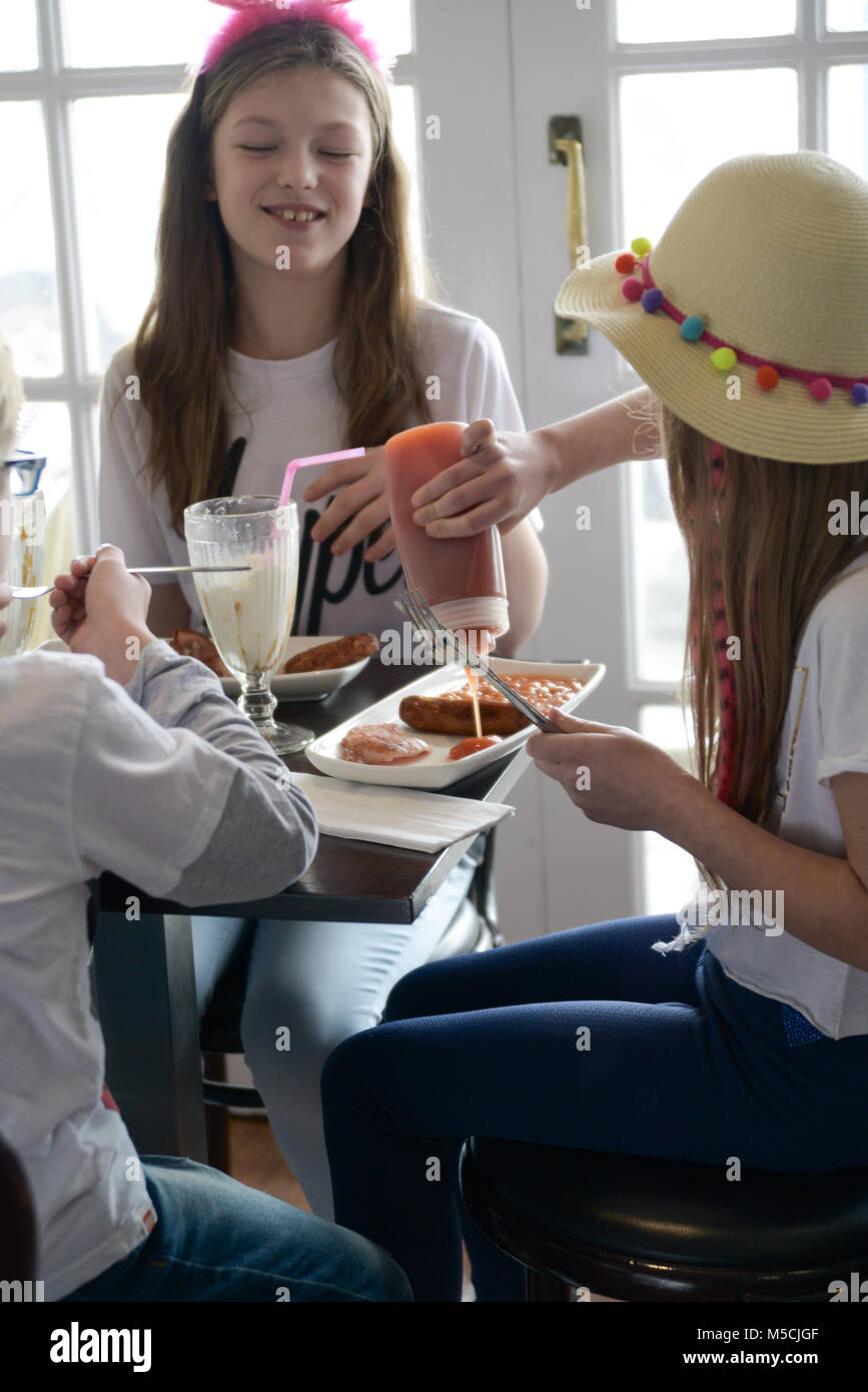 two young children are sitting at a party table eating fried food and ...