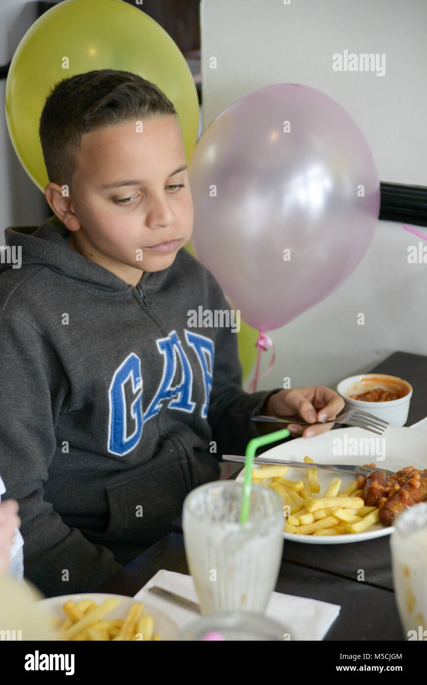 Portrait of a child eating fried food at a party table Stock Photo - Alamy