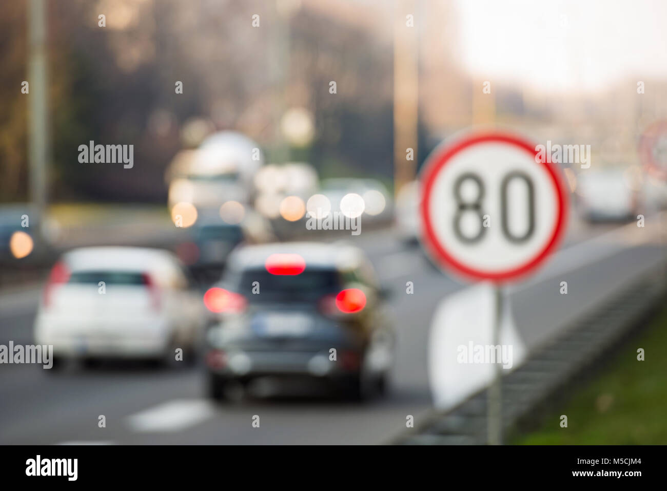 Defocused image of traffic sign showing 80 km/h speed limit on a highway full of cars Stock ...