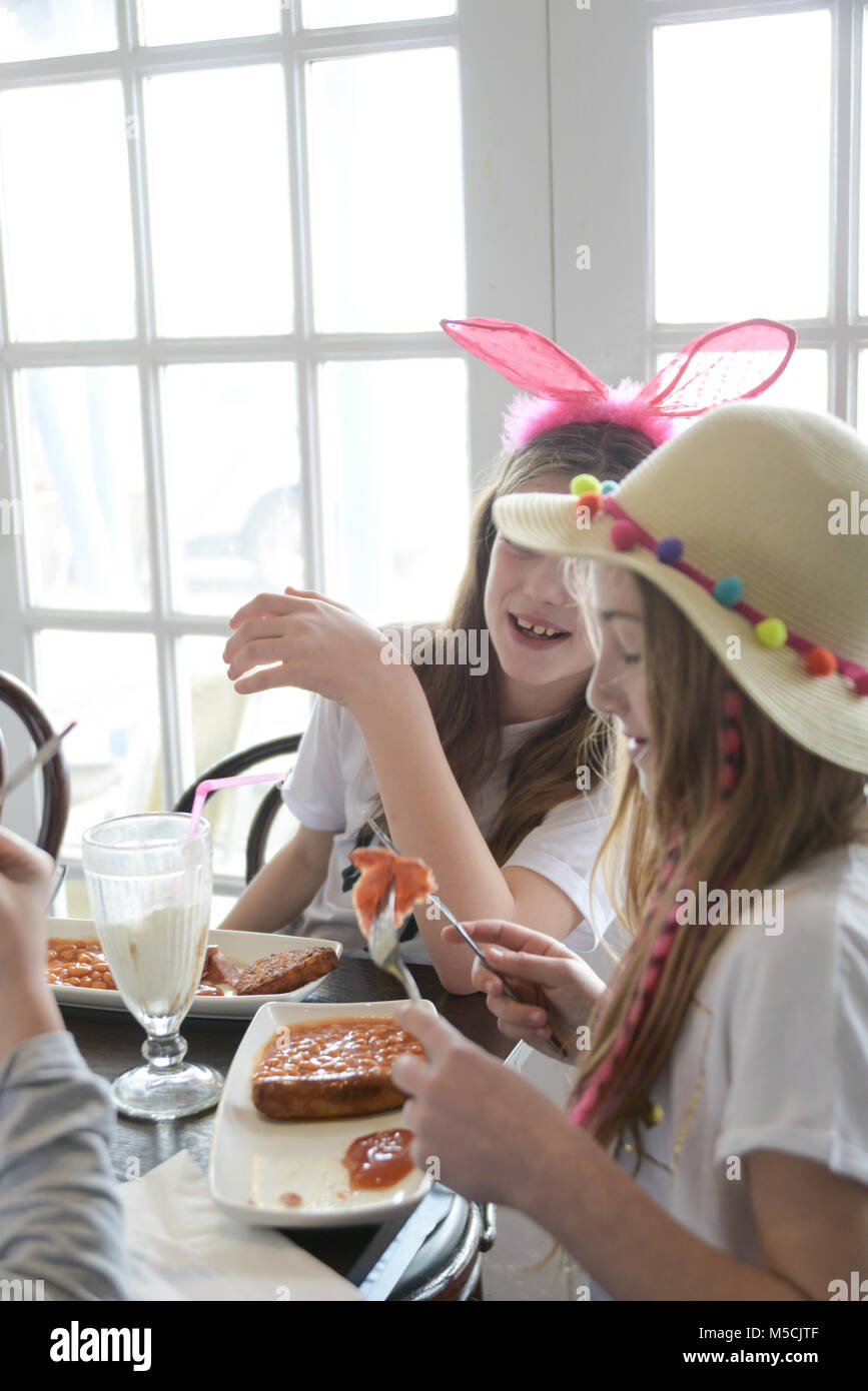 two young children are sitting at a party table eating fried food and ...