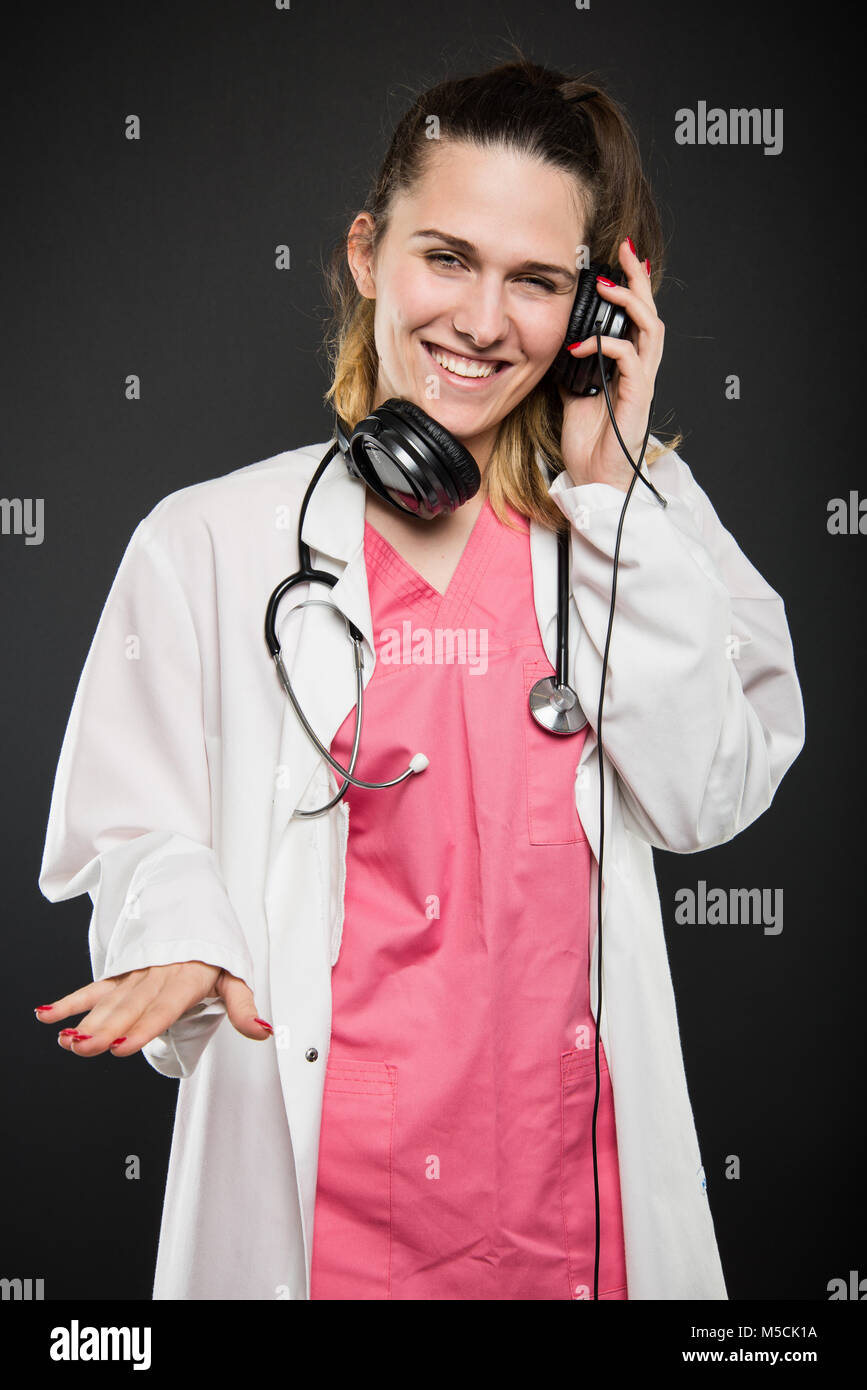 Attractive female doctor wearing headphones acting like a DJ on black ...