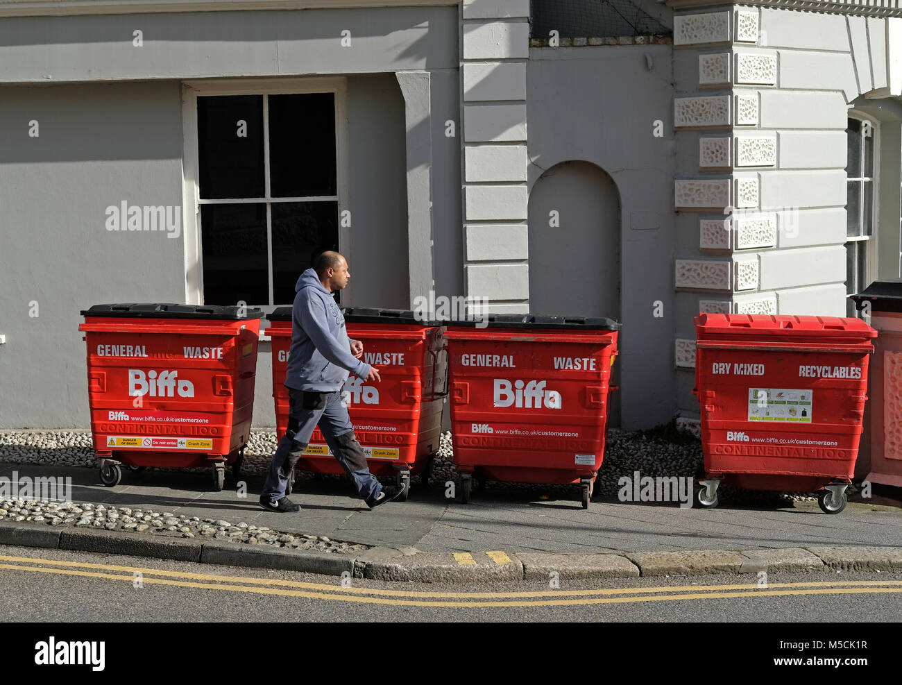 Man walking past rubbish bins Stock Photo - Alamy