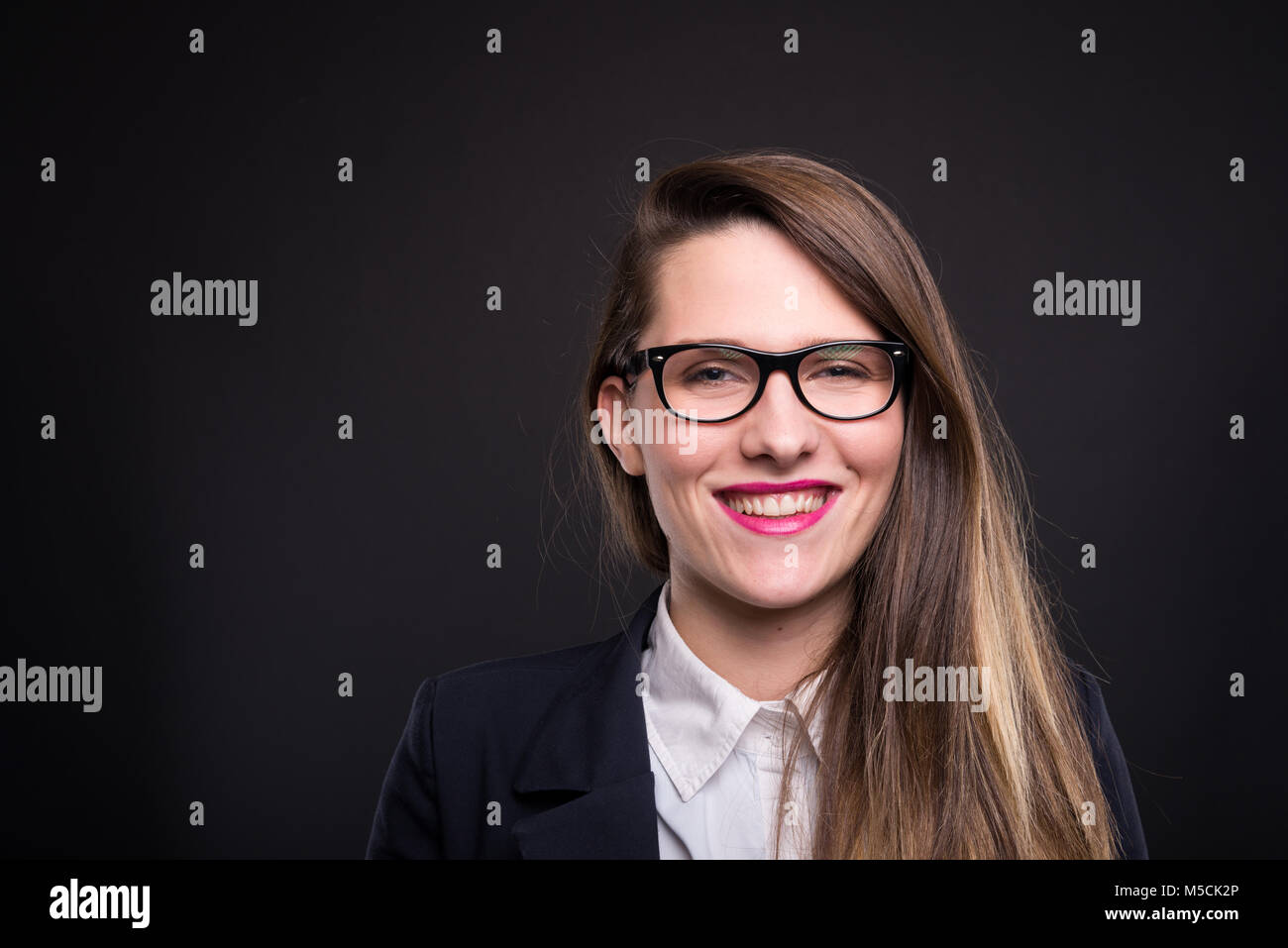 Smiling female bank manager posing on dark background in formal clothes ...