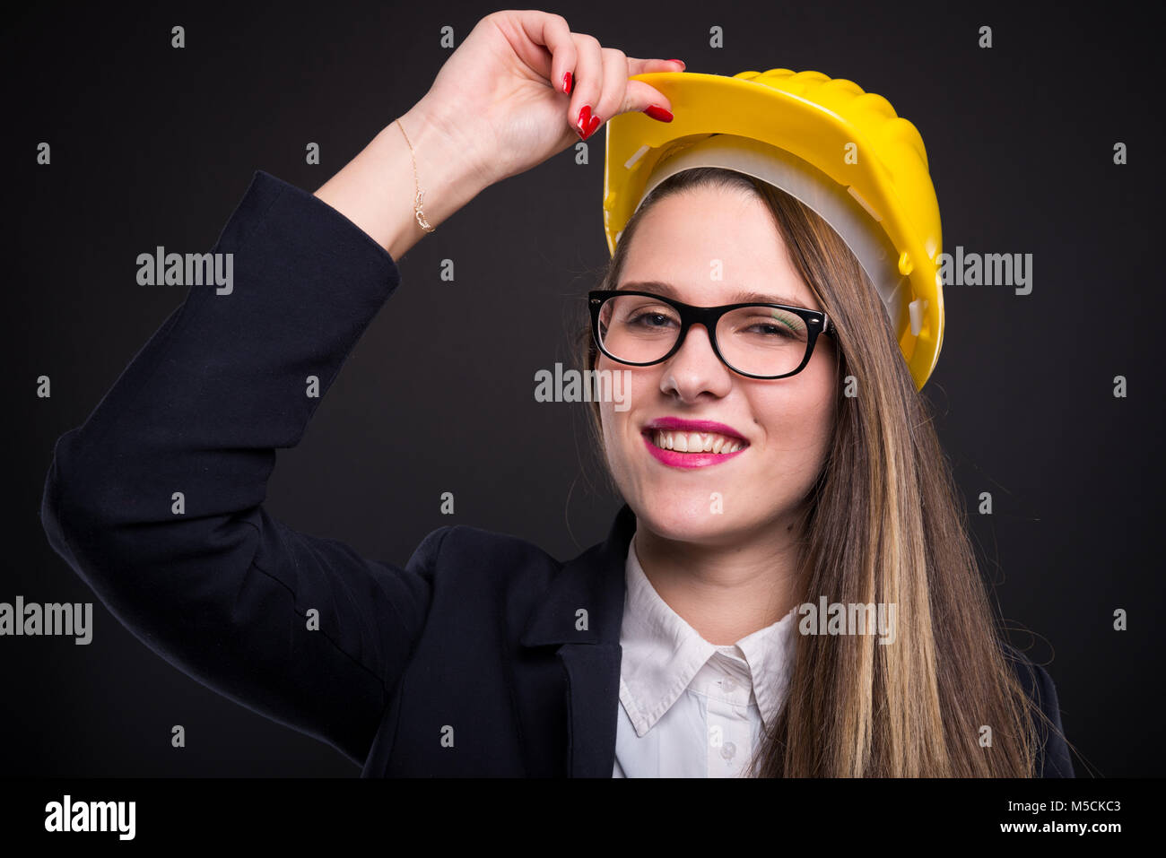 Portrait of smiling happy girl or female engineer with yellow helmet ...