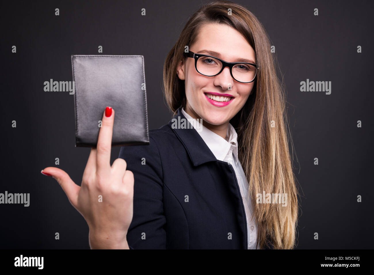 Joyful attractive business woman holding her wallet and smiling on dark ...