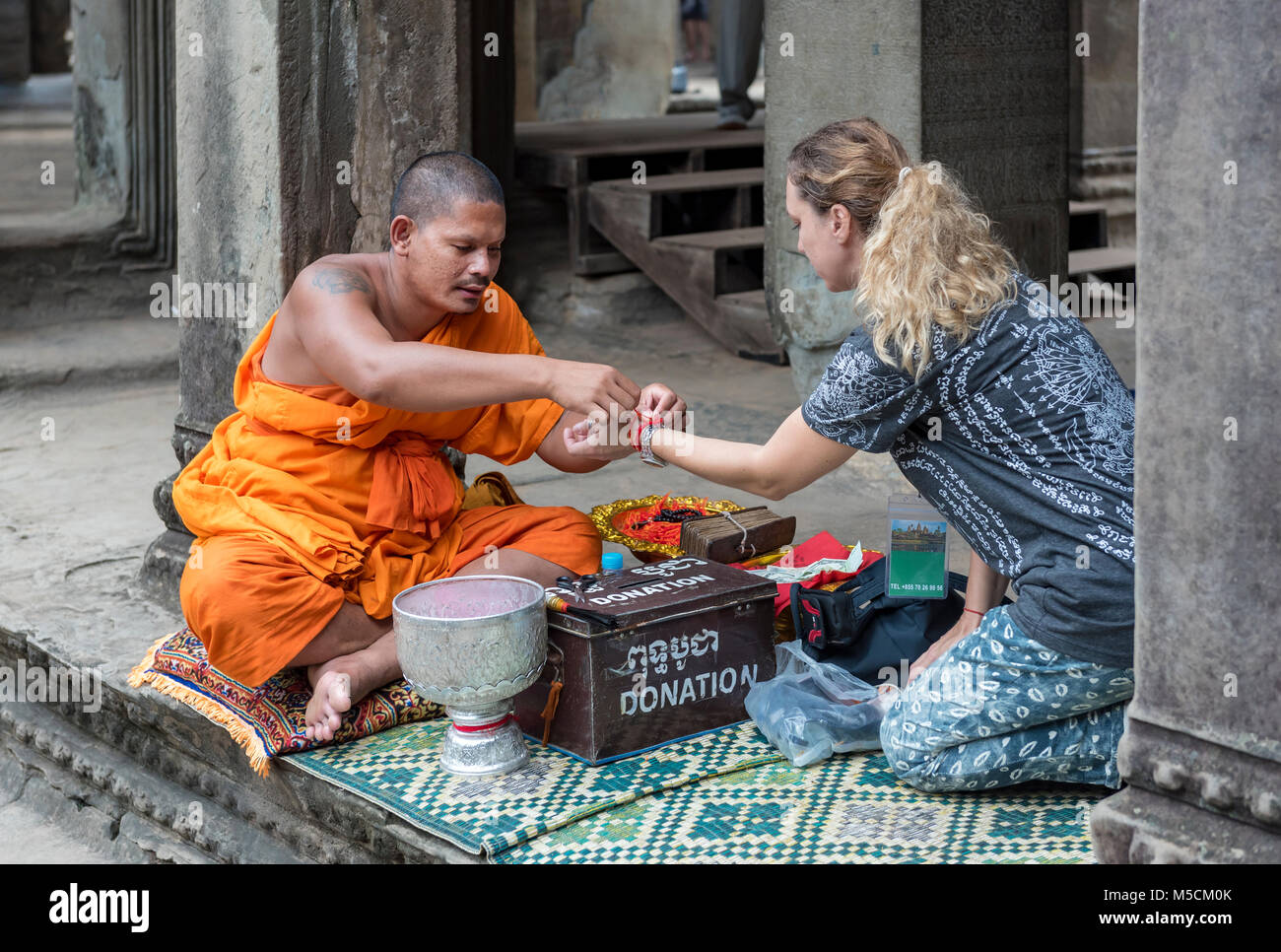 Buddhist monk gives blessing to a Western tourist at Angkor Wat ...