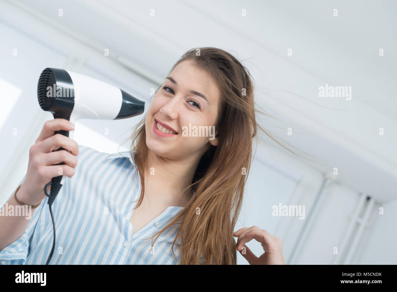 smiling pretty young woman is drying her hair Stock Photo - Alamy