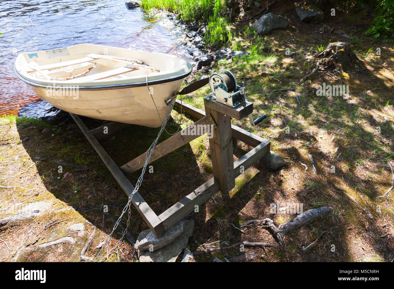Small plastic white rowboat lays on coast of still lake. Construction ...