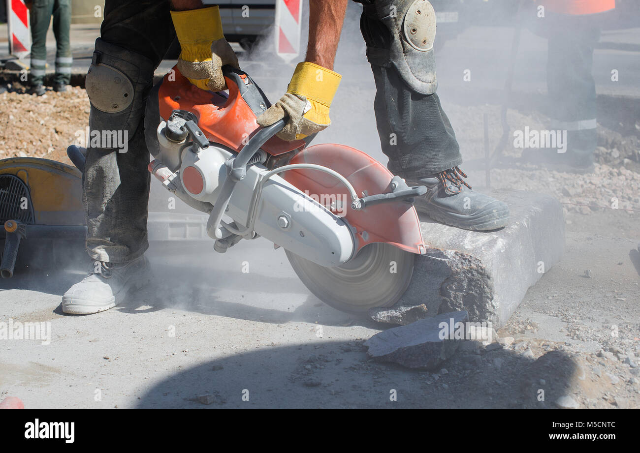 Builder worker with cut-off machine power tool breaking concrete at ...