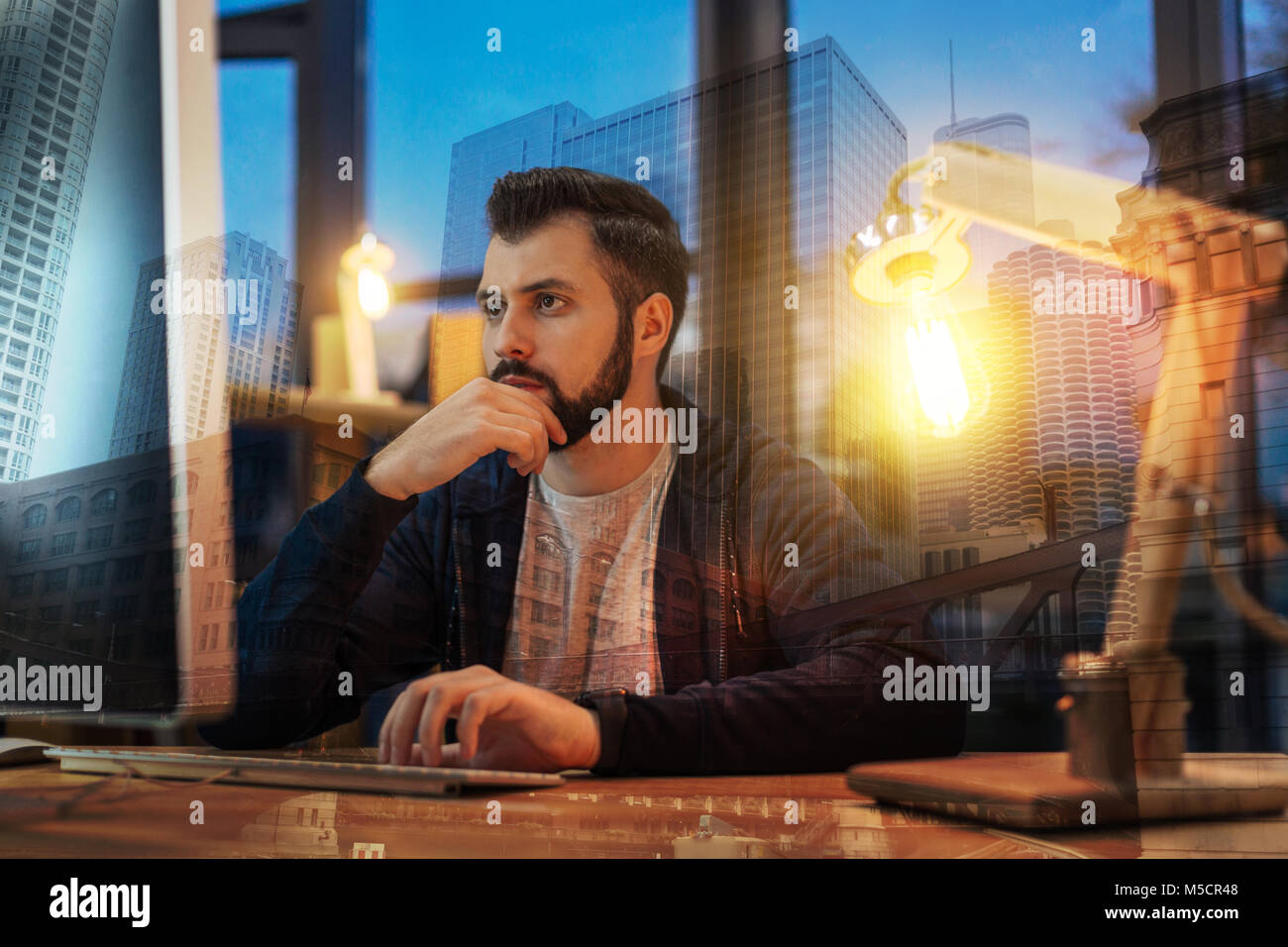 Clever man sitting with his hand touching his chin and thinking Stock ...