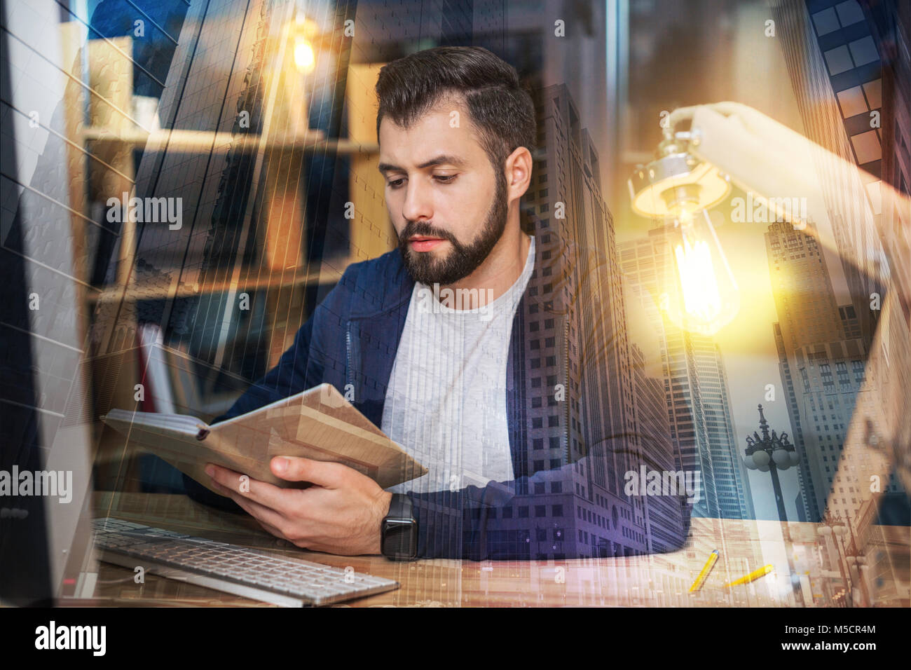 Calm man reading a book while sitting alone in his office Stock Photo ...