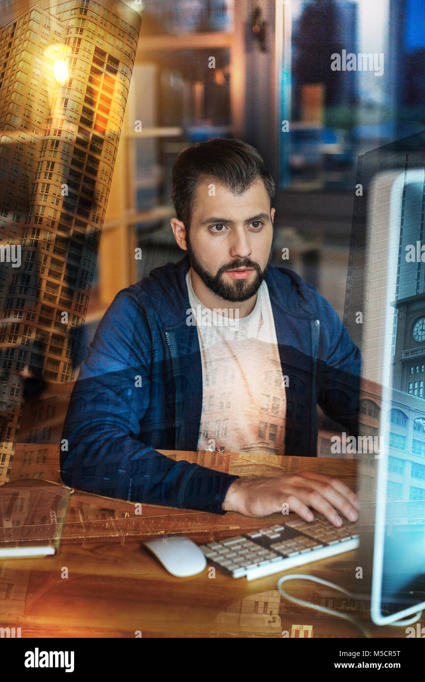 Concentrated man looking at the monitor while working in his office ...