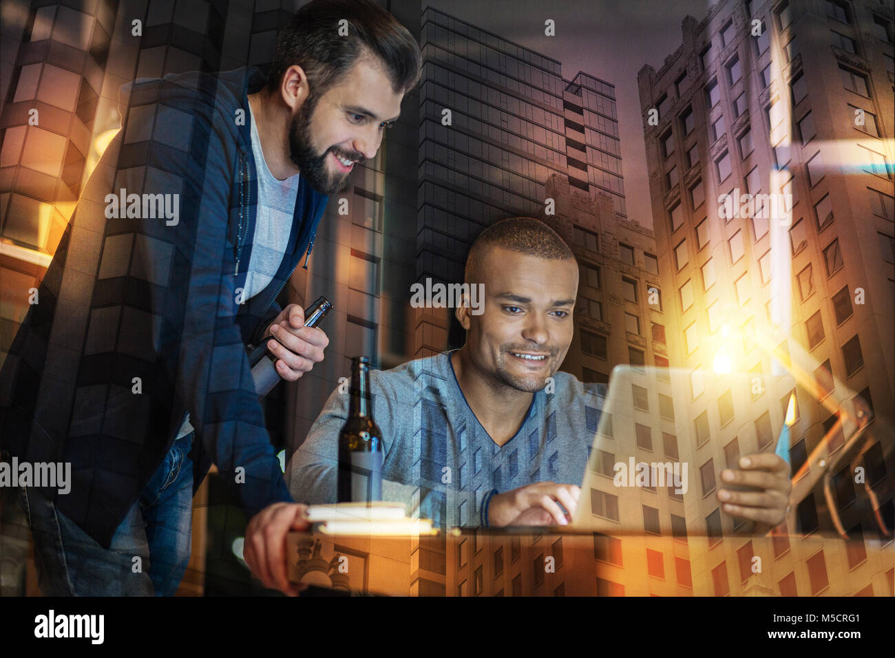 Young man looking at the screen while his friend standing near Stock ...