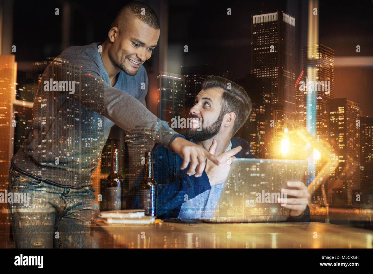 Emotional man pointing to the screen while his friend looking at him ...